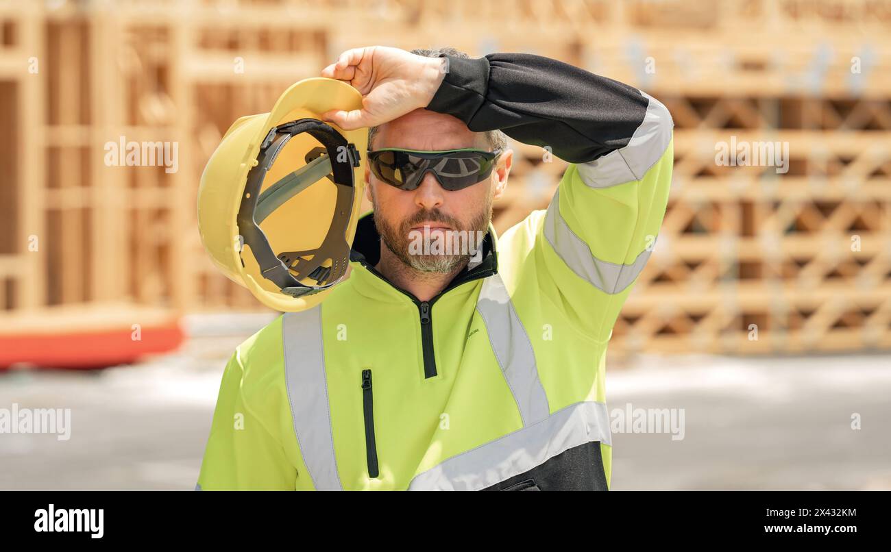 Tired, overworked worker in building uniform on buildings construction ...