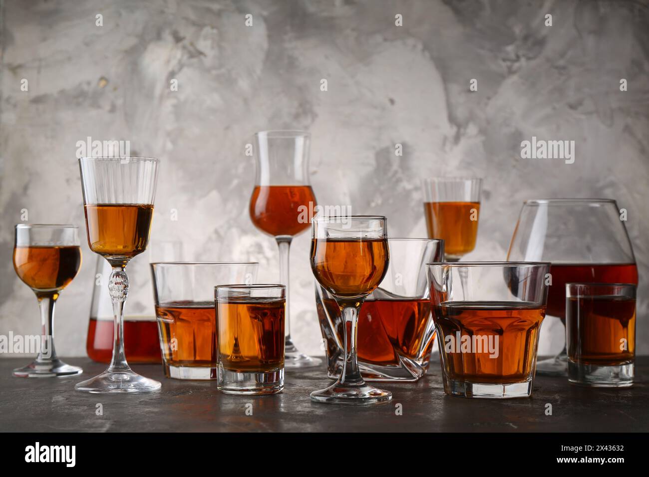 Different delicious liqueurs in glasses on grey table Stock Photo - Alamy