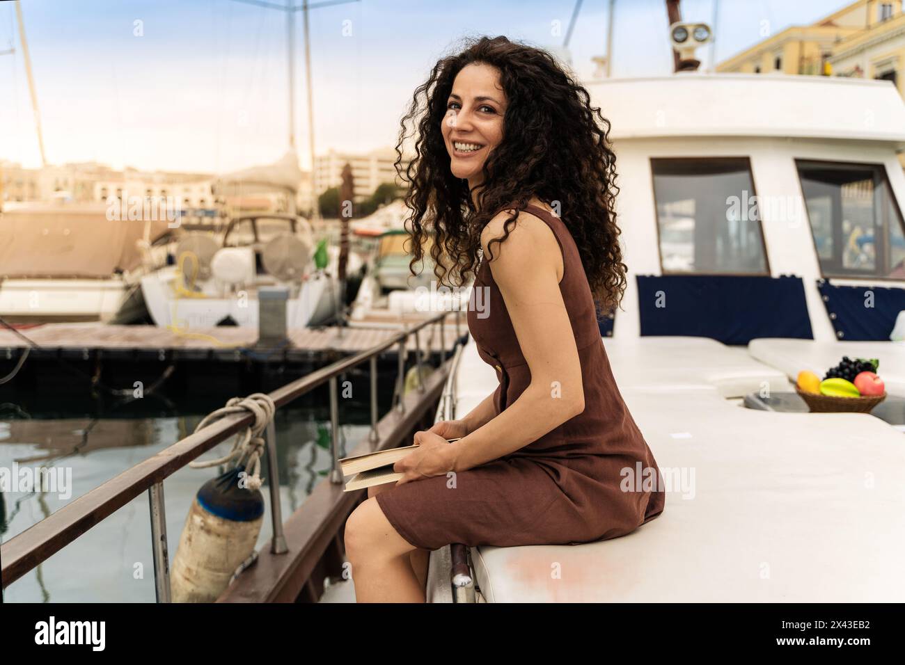 A cheerful woman enjoys reading a book on a yacht - relaxed lifestyle ...
