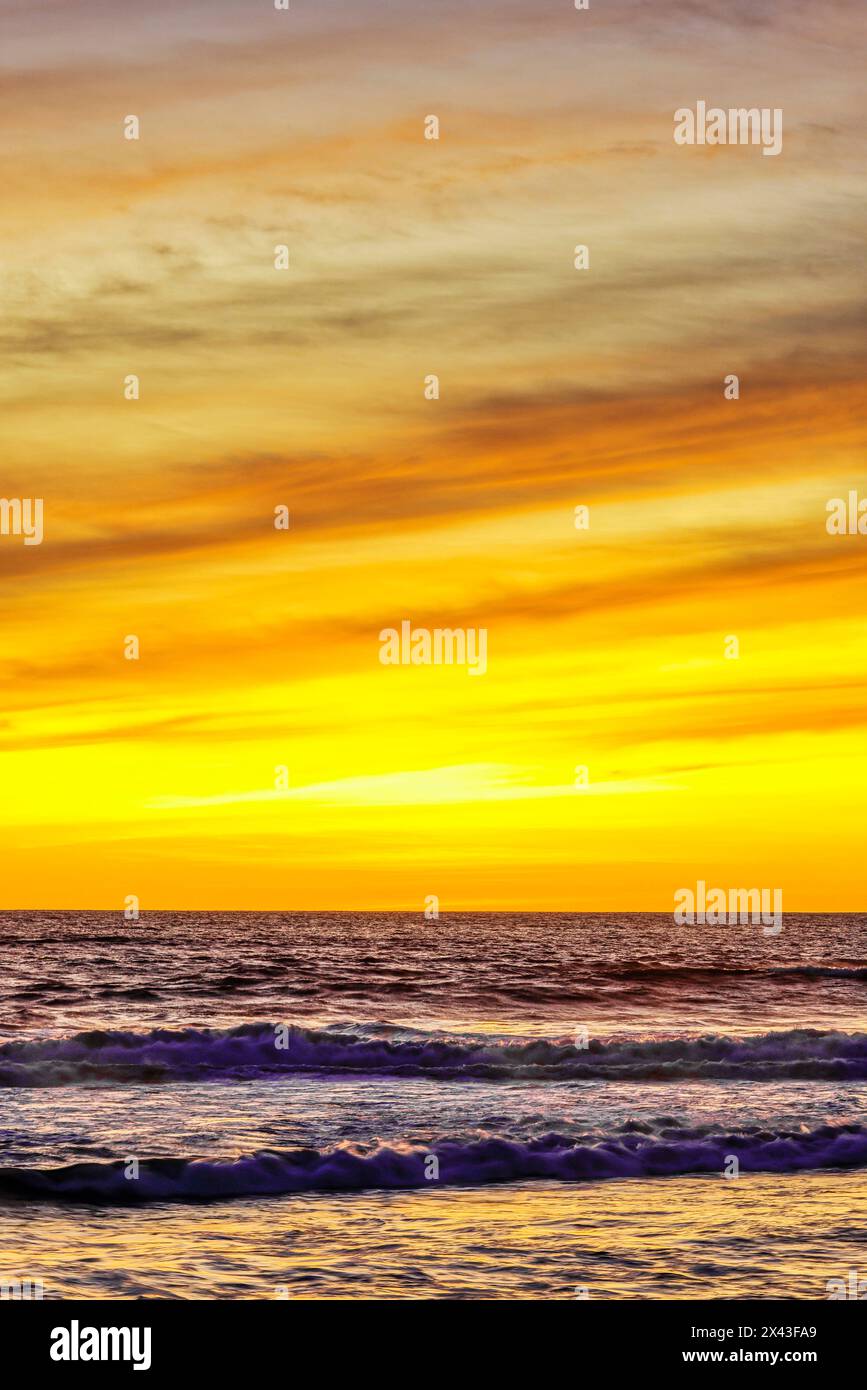 The golden light of the setting sun reflects a gold glow on the beach ...