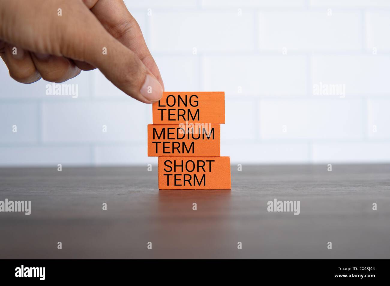 Hand pick wooden cube with text LONG TERM on blue background with copy ...