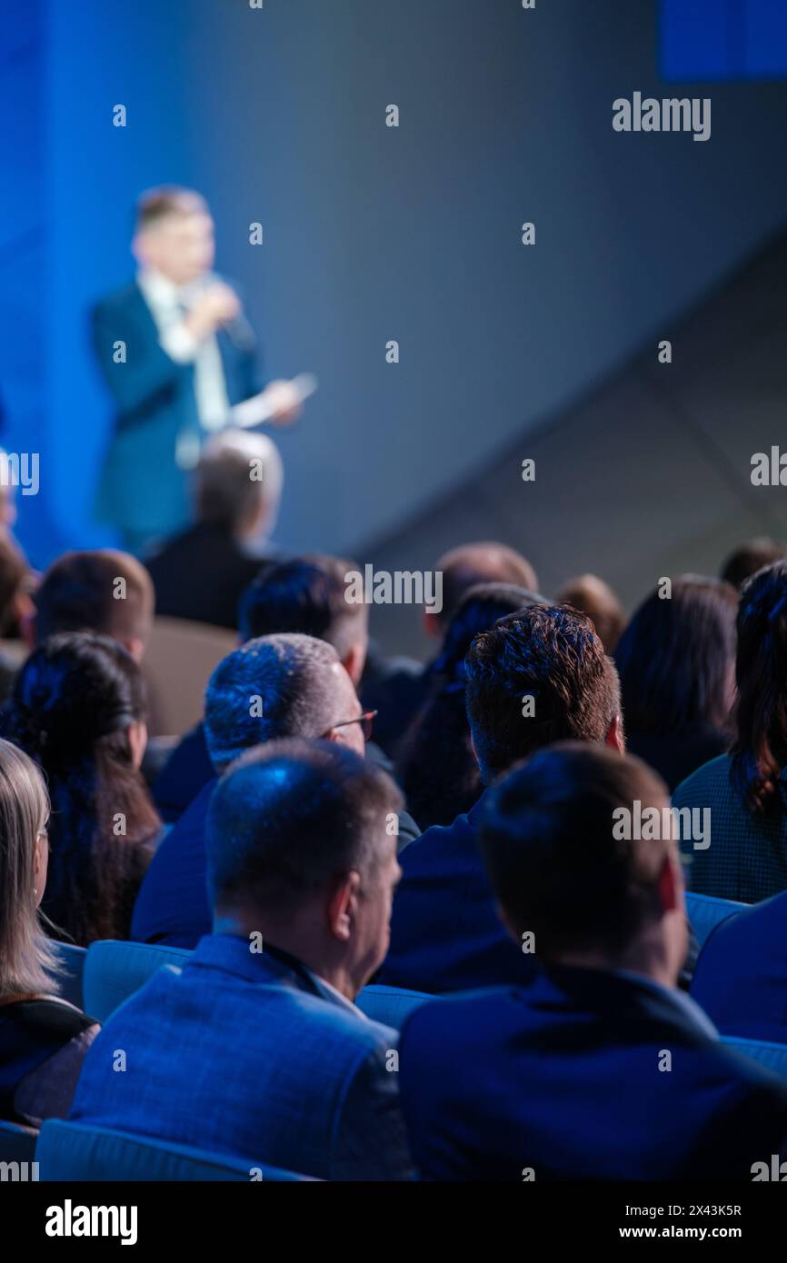 Frofessional speaker in a suit speaking to an attentive audience at a ...