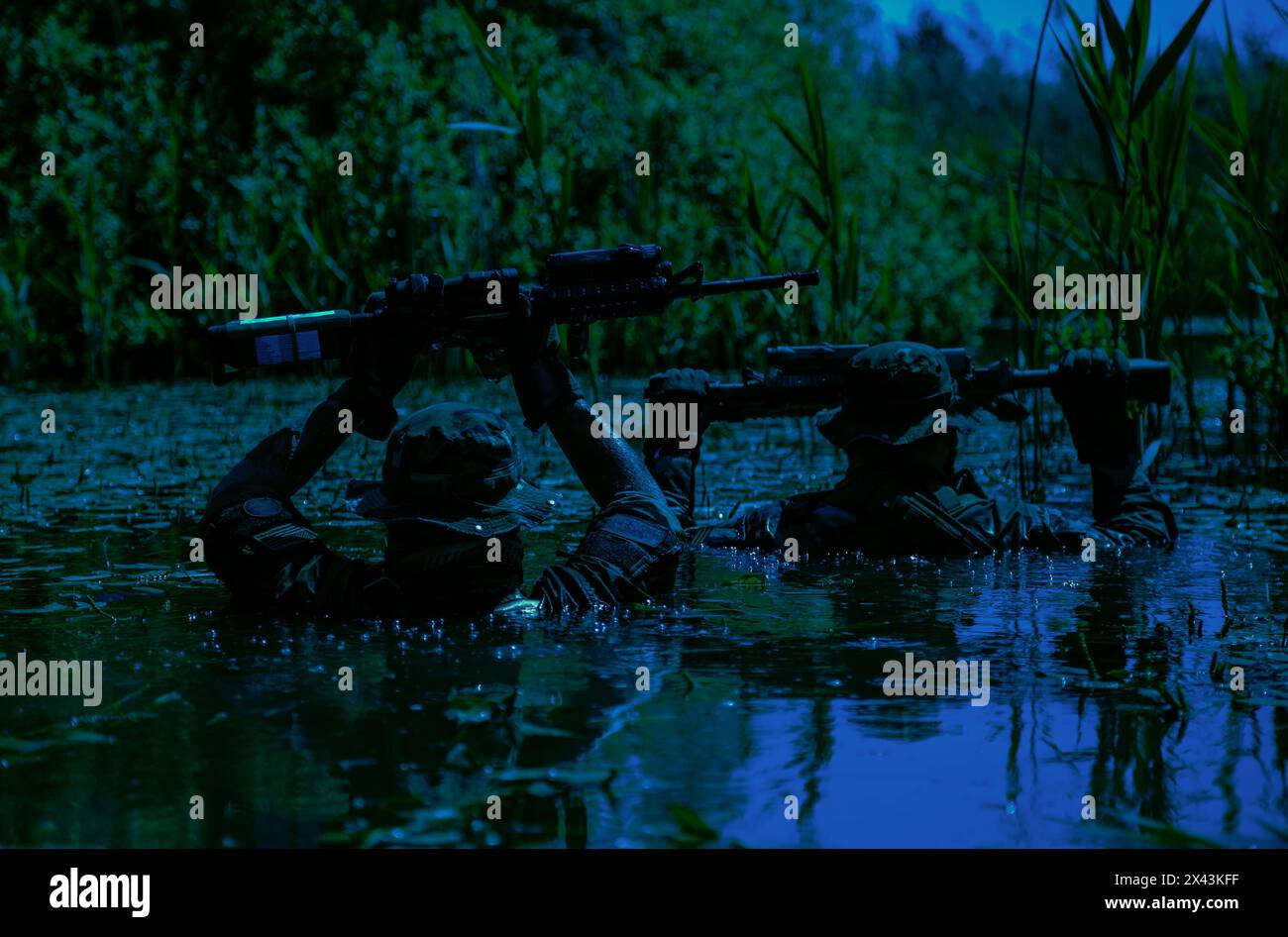 Soldiers move in the heart of a marsh, submerged in swampy waters with ...