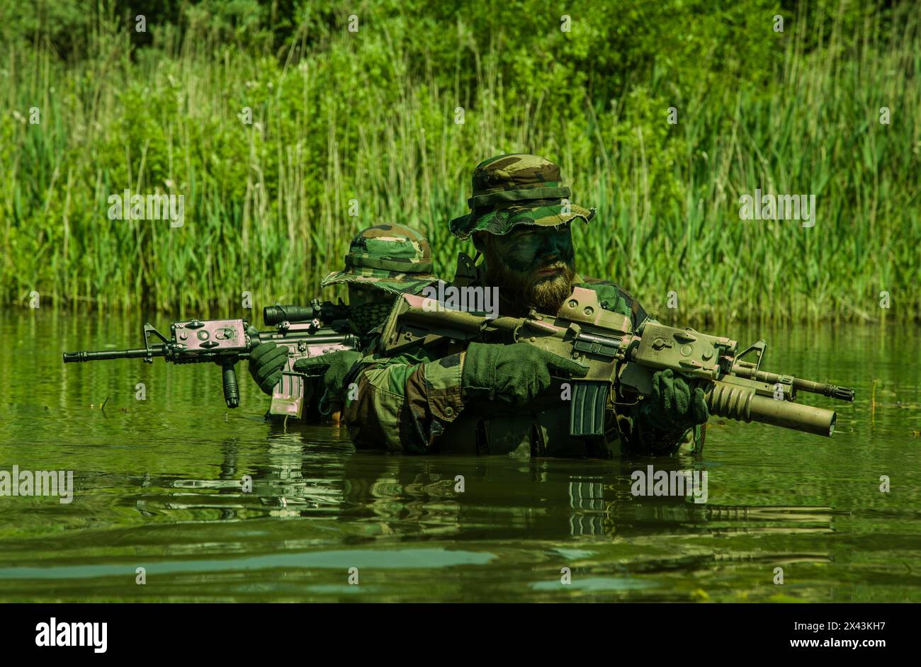 Soldiers move in the heart of a marsh, crossing swampy waters, tropical ...