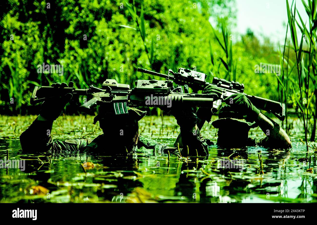 Soldiers move in the heart of a marsh, submerged in swampy waters with ...