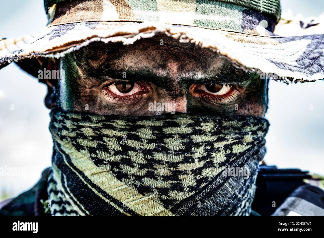 Gaze of a soldier, face shrouded in a scarf and under a combat hat ...