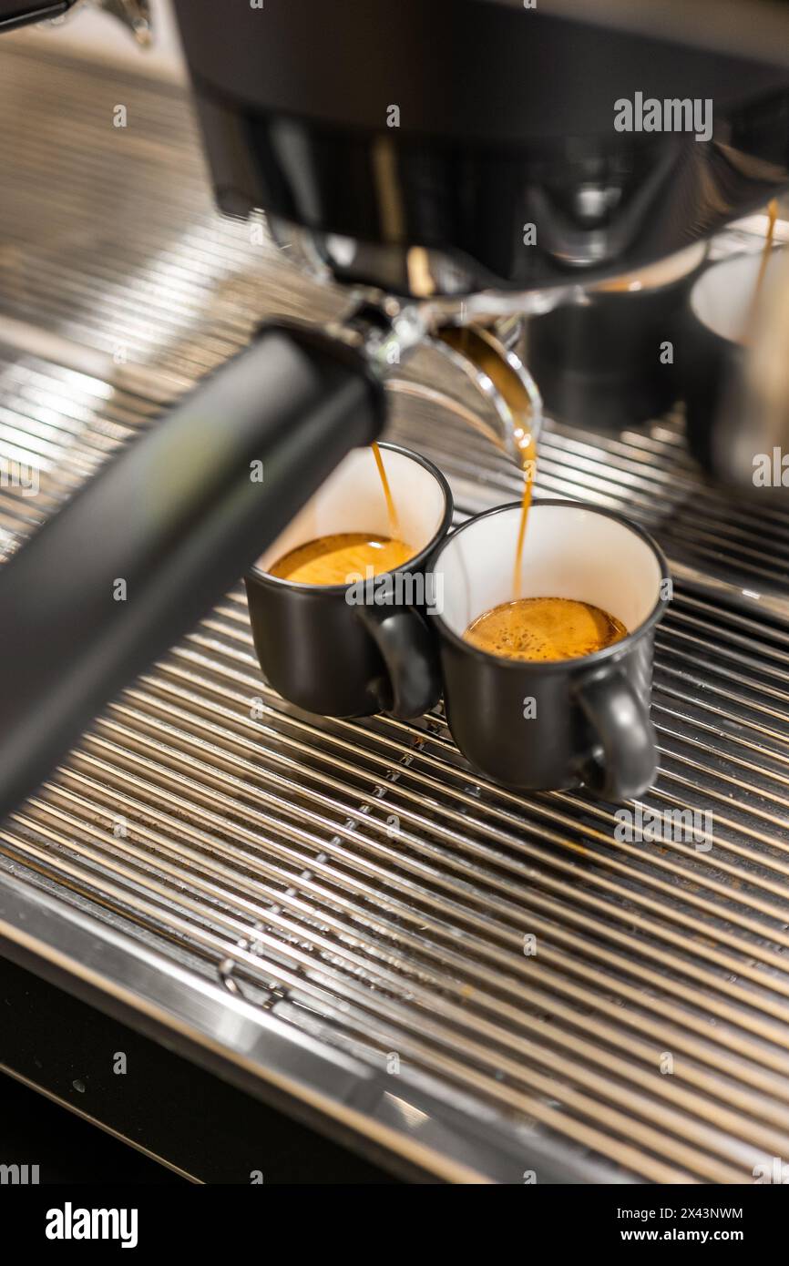 Espresso machine pouring fresh coffee into two black cups Stock Photo ...
