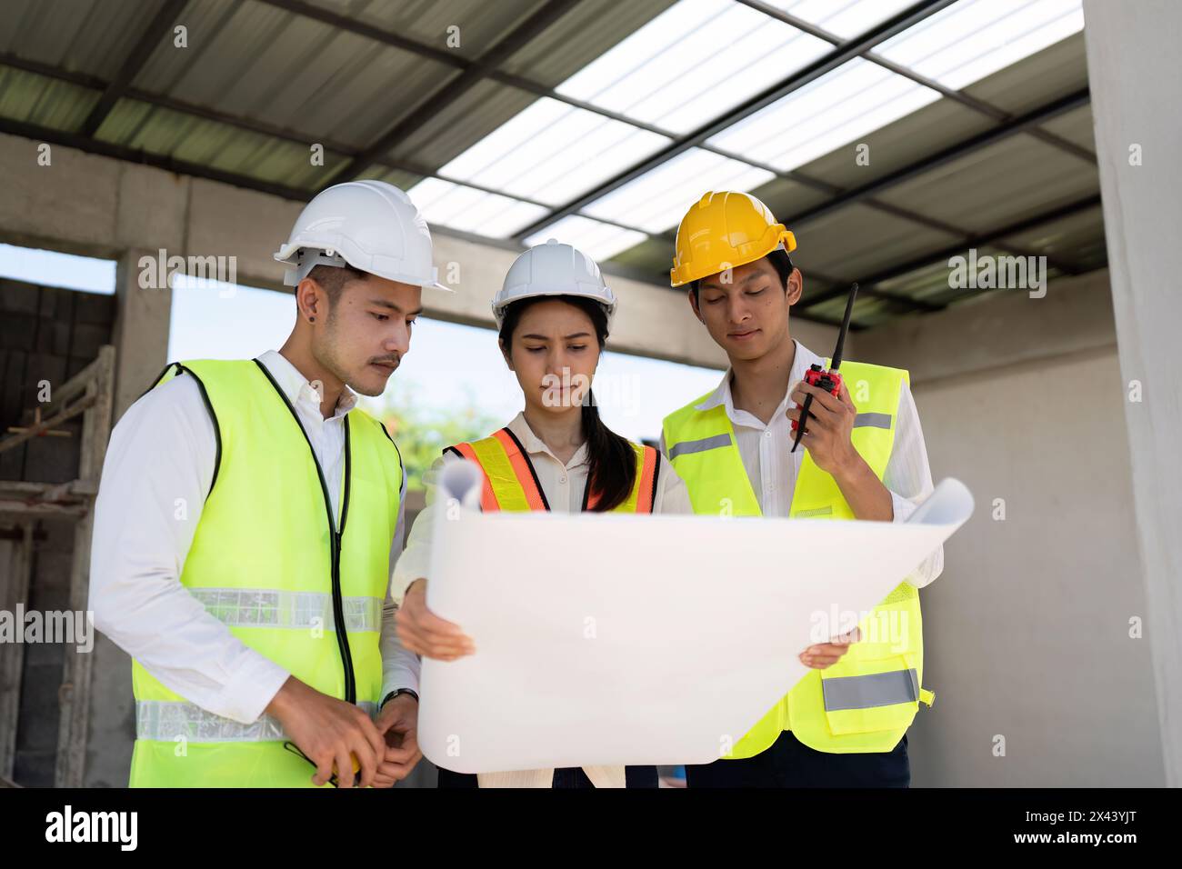 team of engineers is looking at blueprint construction and discussing ...