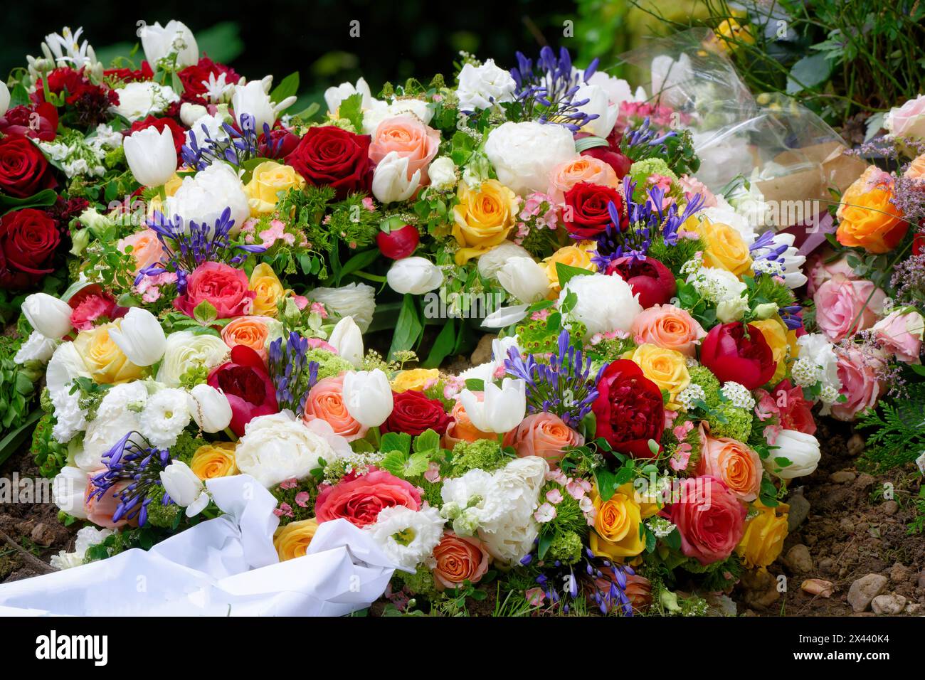 a funeral wreath with a white ribbon and many colourful flowers on a ...