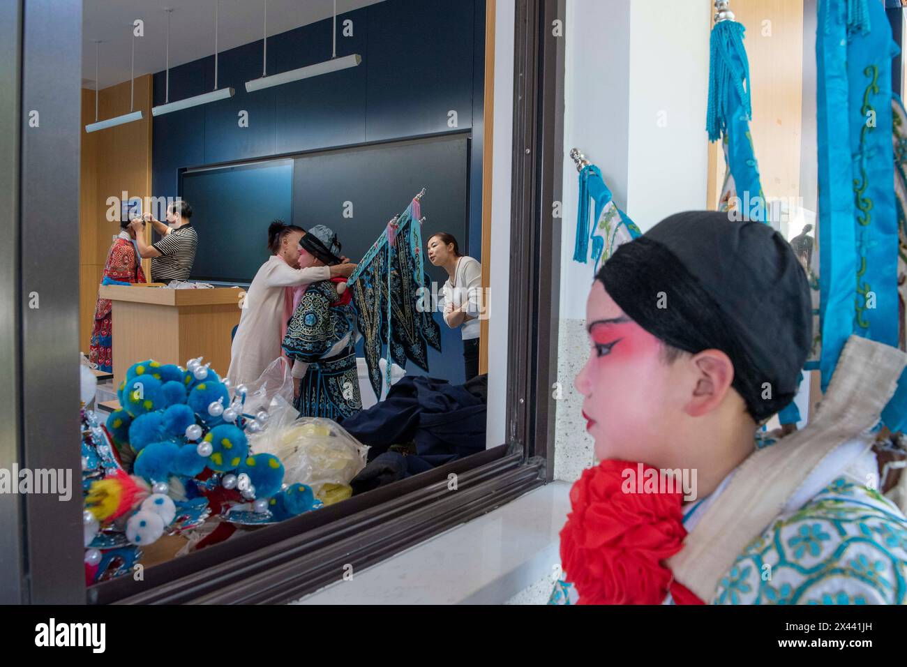 A teacher is dressing children in costumes for a Peking Opera troupe in ...