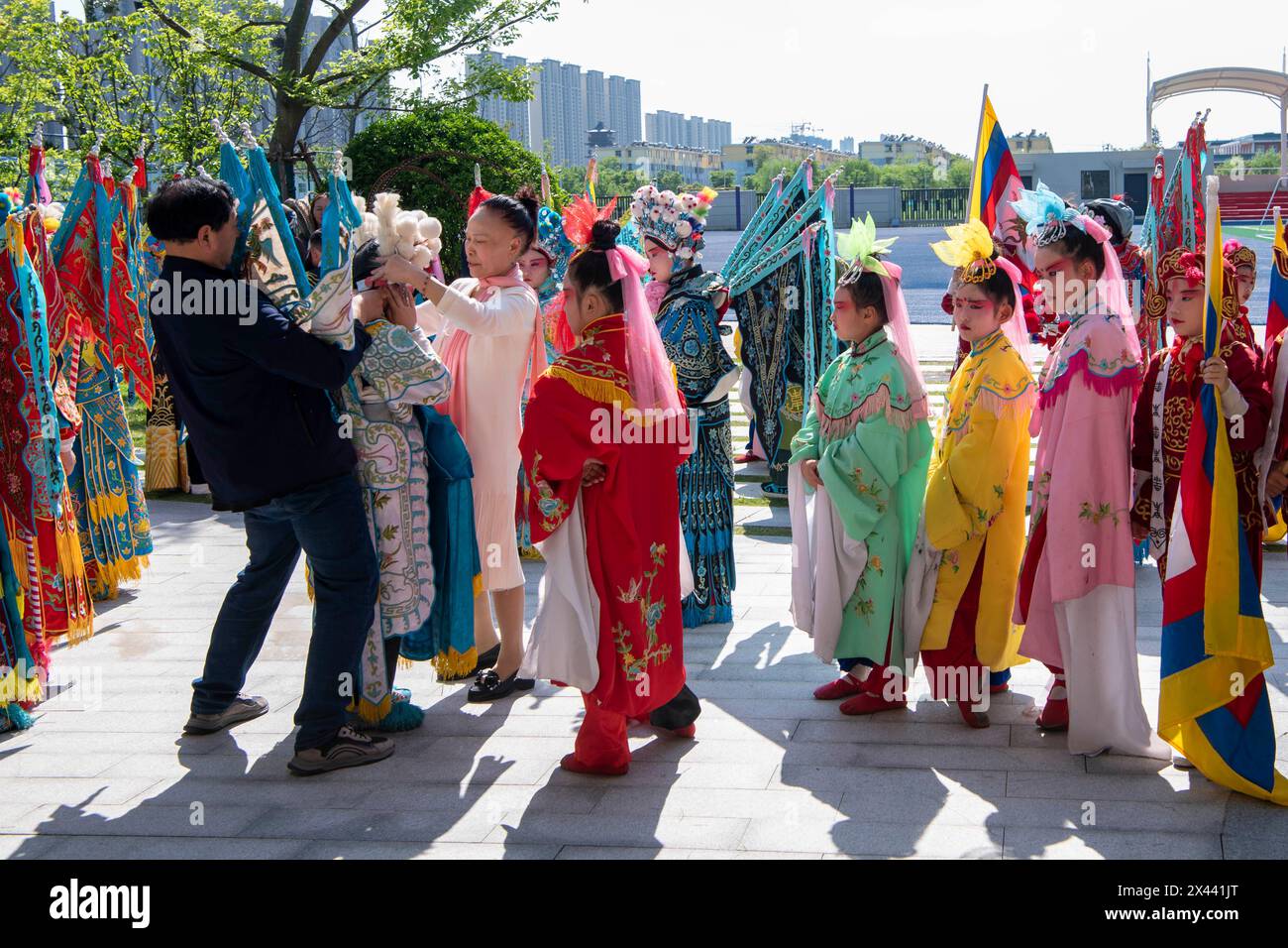A teacher is putting headgear on children of a Peking Opera club who ...