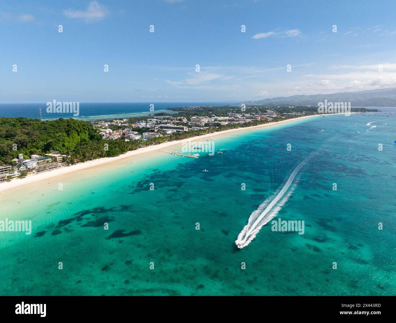 Powdery white sand beach with waves and boats running over the ...