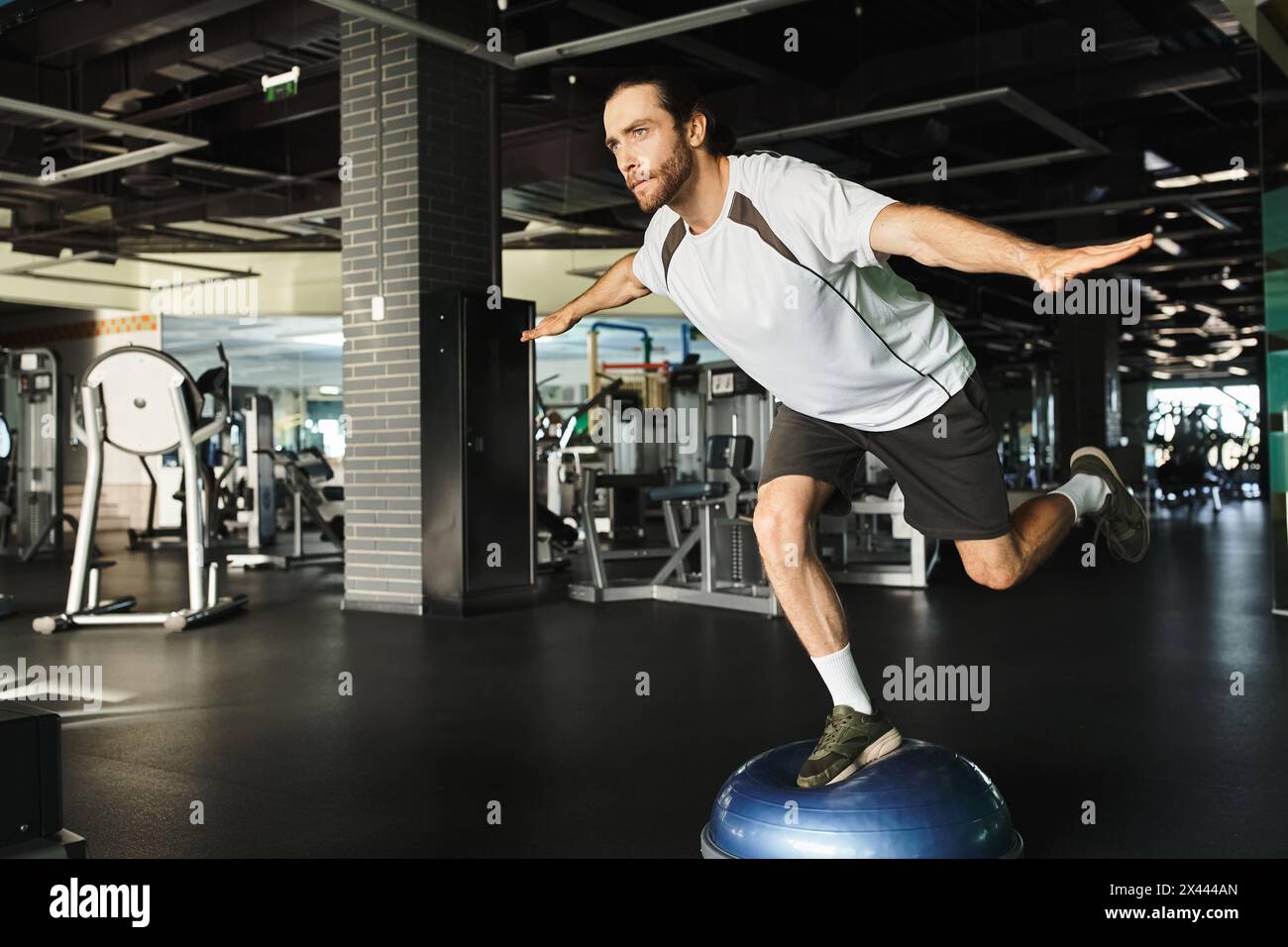 A muscular man creatively performs exercises on an exercise ball in a ...