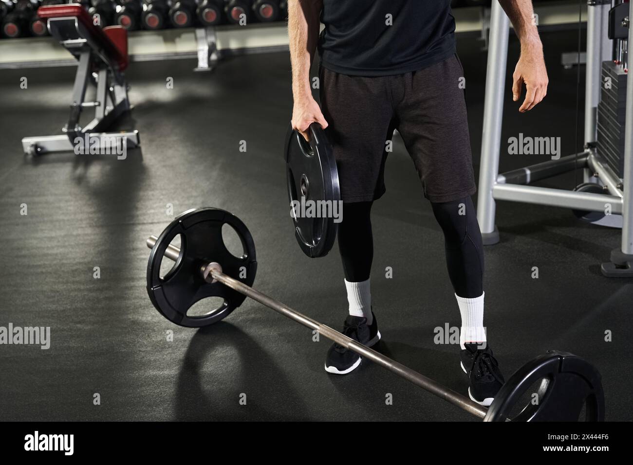 Athletic man in gym near barbell, showcasing strength and determination ...