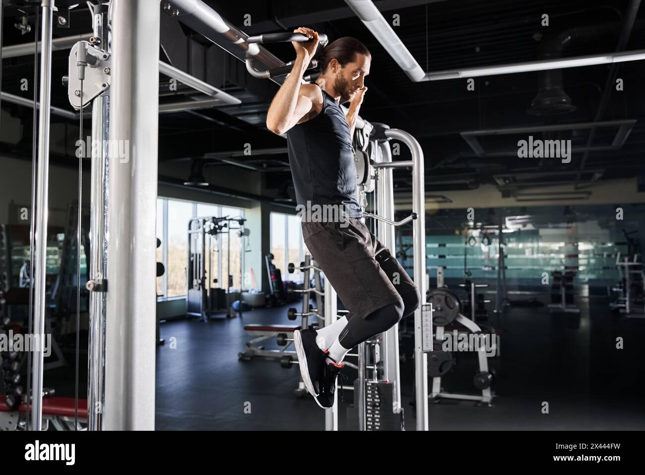 An athletic man in active wear is conquering pull ups with ...