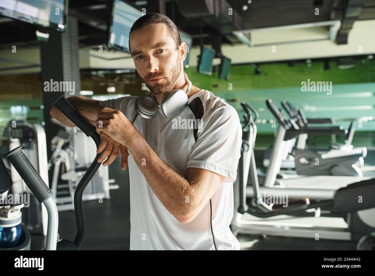 A fit man in activewear is using a treadmill in a gym for his workout ...