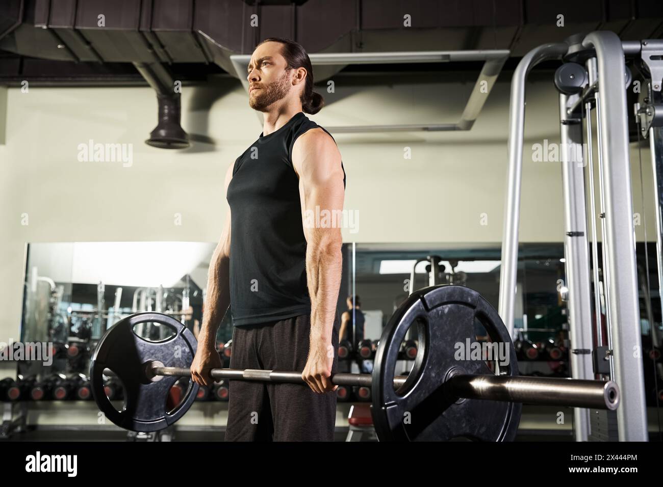 An athletic man in active wear stands in a gym, holding a barbell with ...