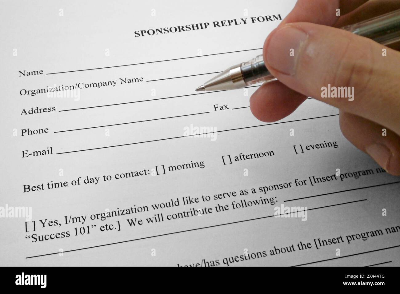 Ballpoint pen hold in the hand of a man filling a sponsorship reply ...
