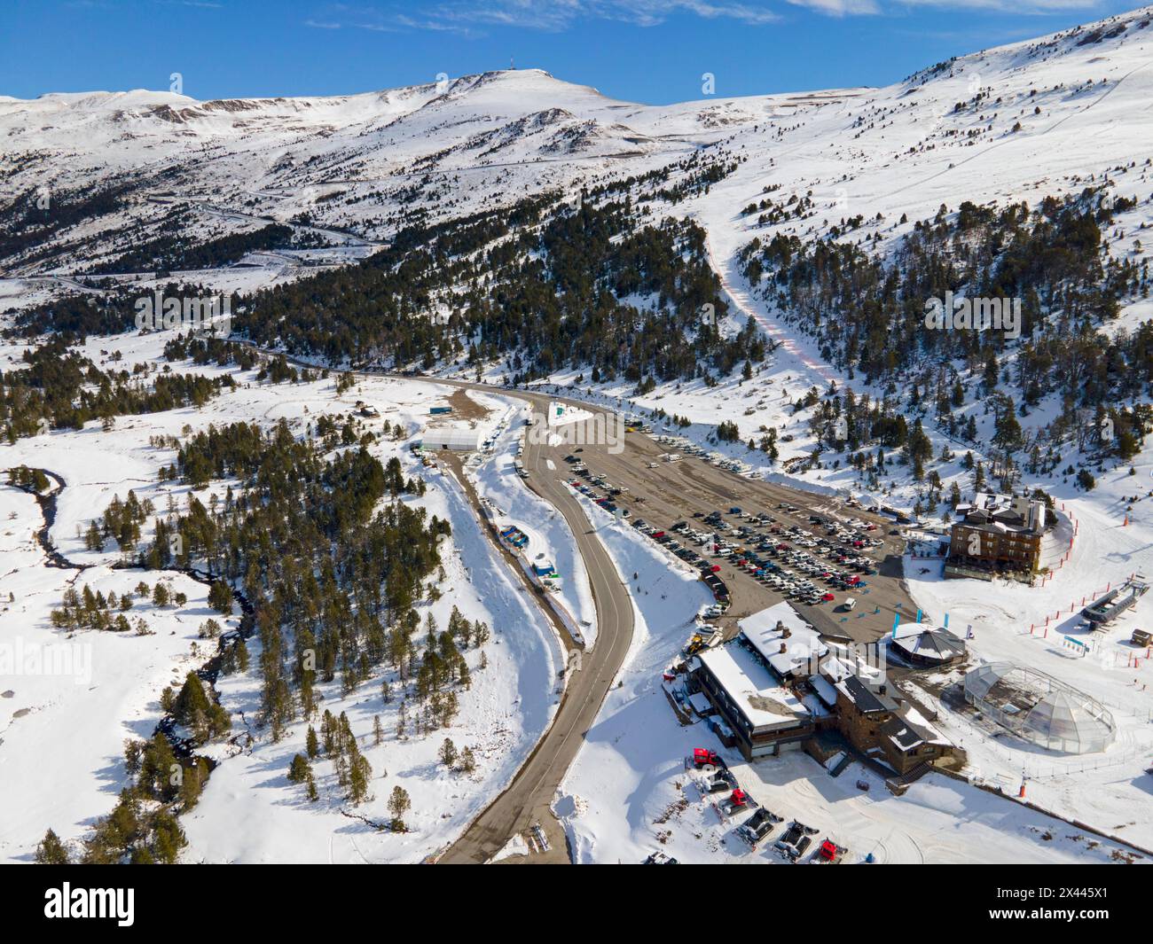 Aerial view of a snow-covered ski resort with car park and clear blue ...
