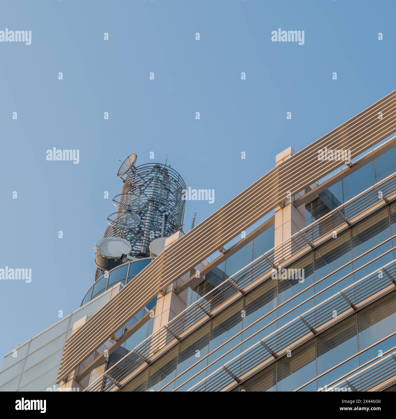 Large circular communication tower on roof of modern building with blue ...