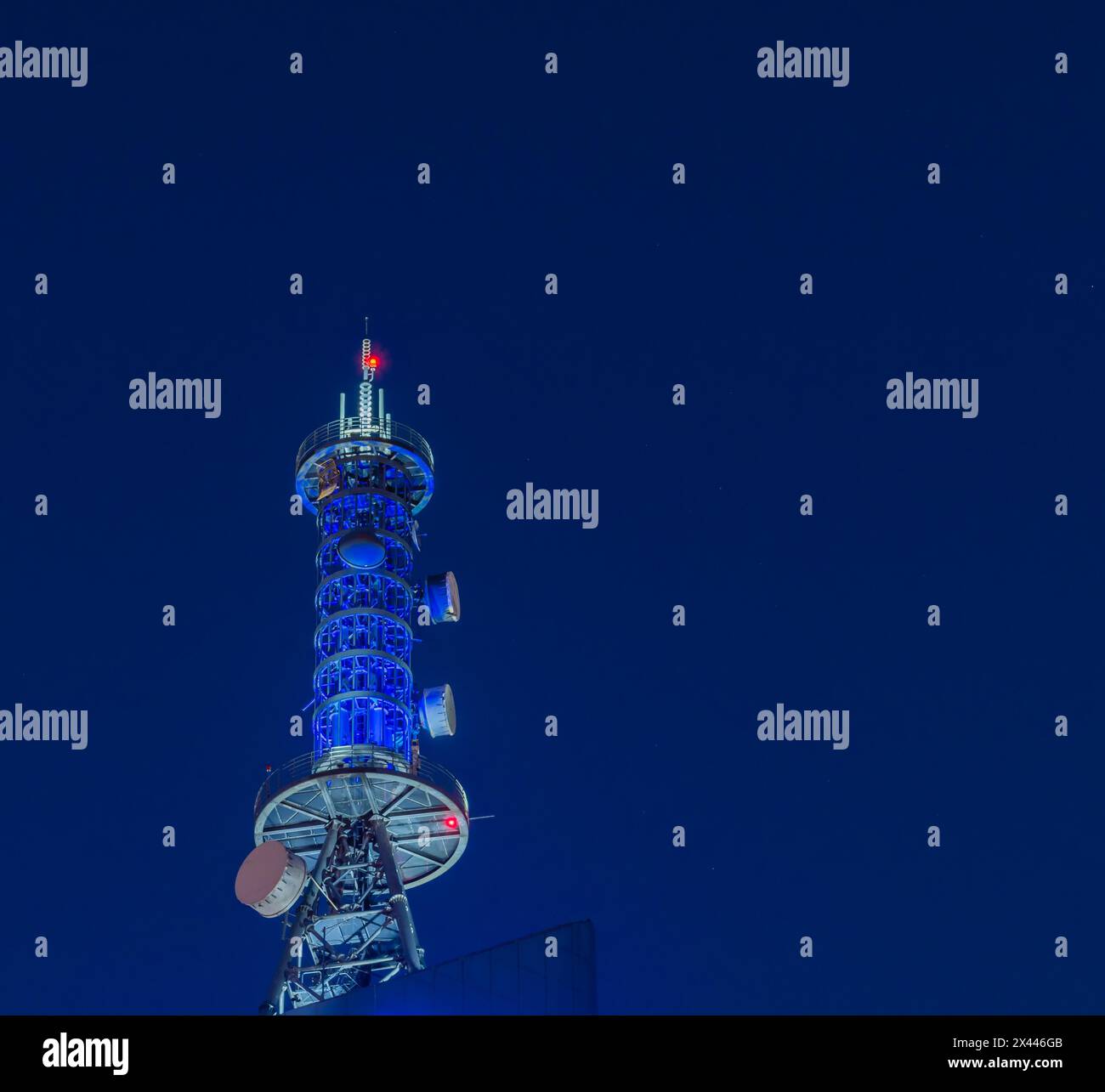 Low angle night view of large communication array tower lit up in blue ...