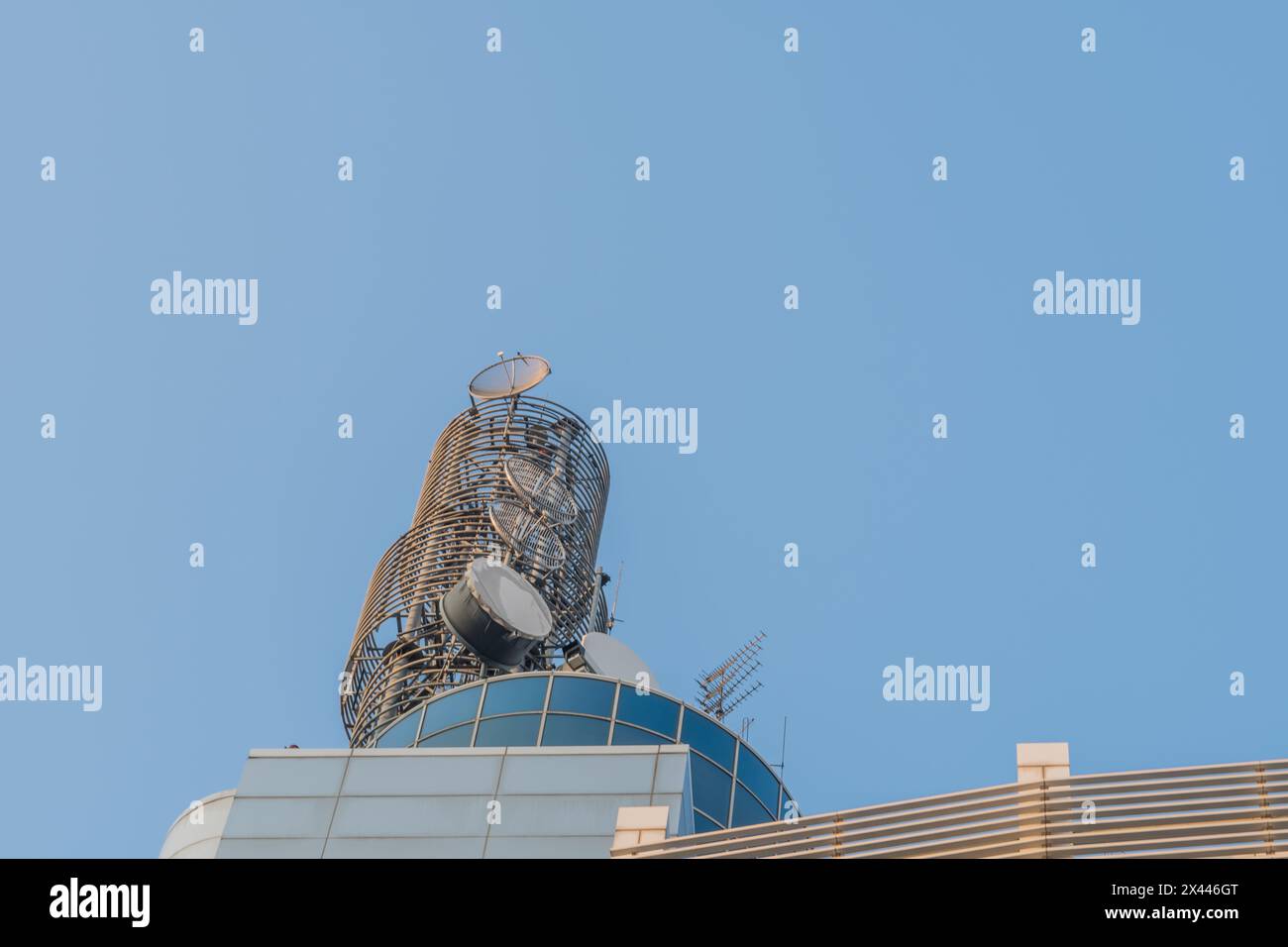 Large circular communication tower on roof of modern building with blue ...