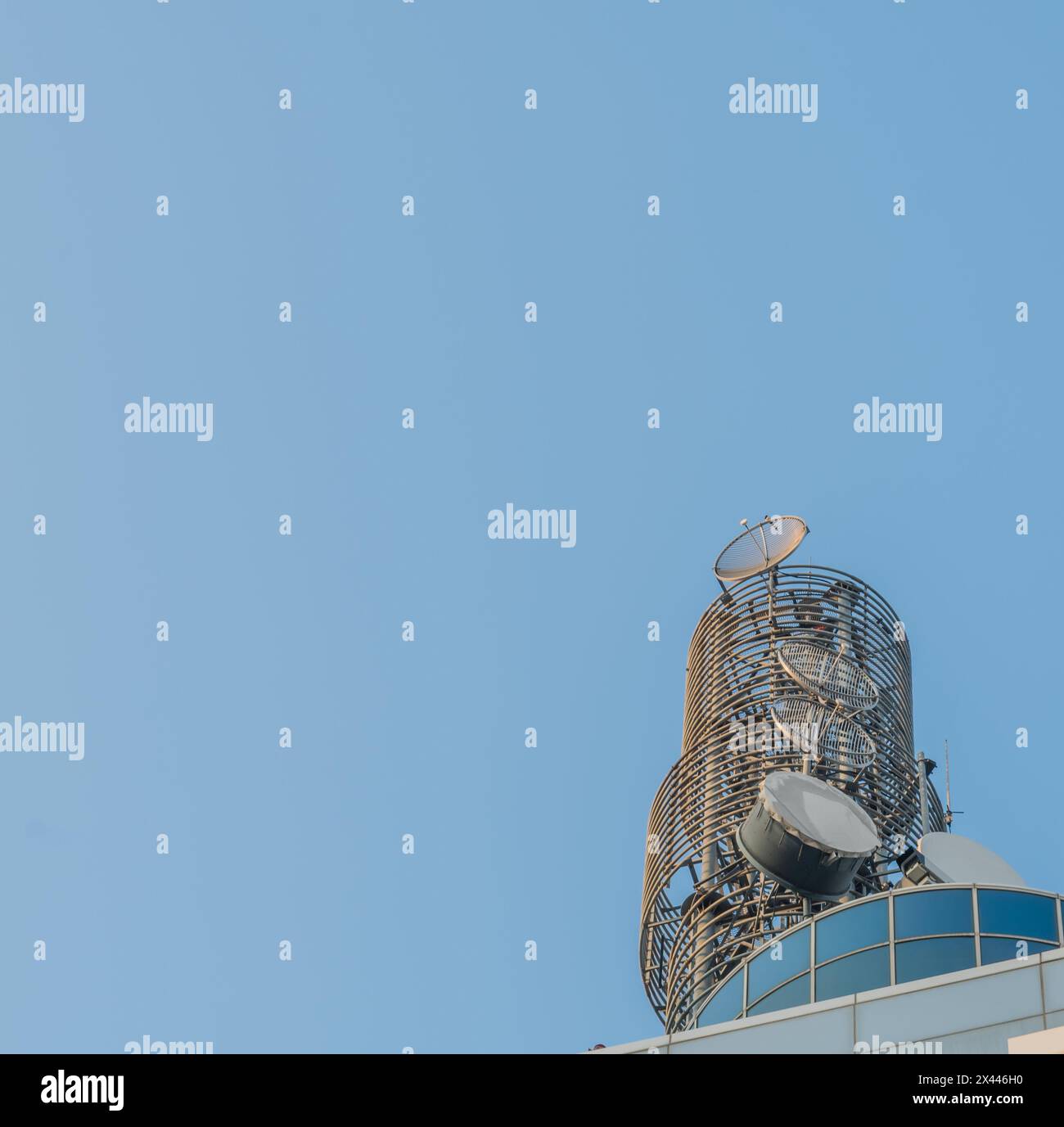 Large circular communication tower on roof of modern building with blue ...