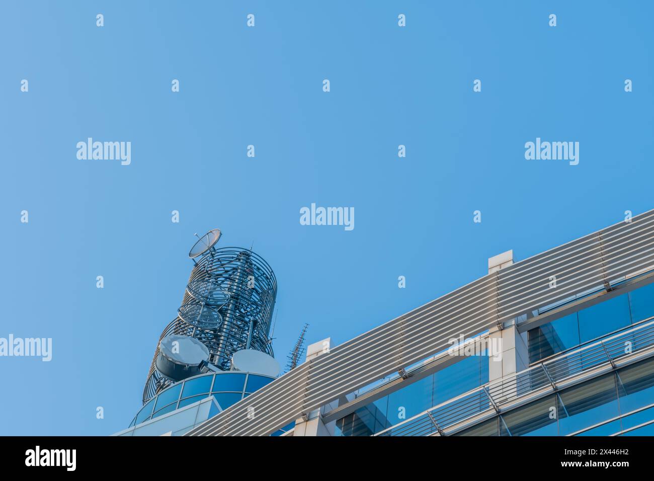 Large circular communication tower on roof of modern building with blue ...