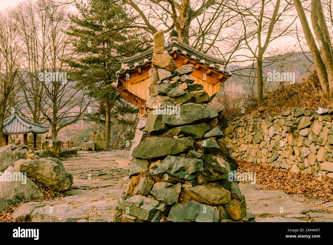 Stone and rock cone shaped tower in front of small wooden oriental ...