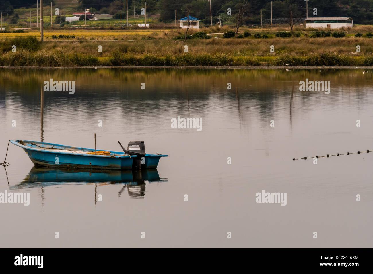 Small blue fishing boat with outboard motor in the middle of lake with ...