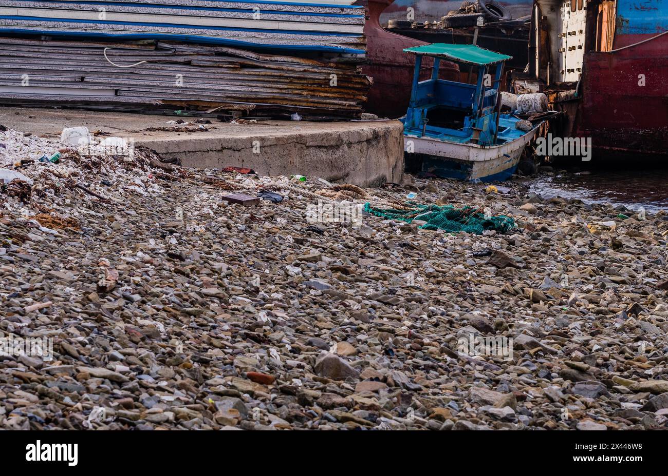 Old rusty abandoned ships sitting on the shore amid trash and debris at ...