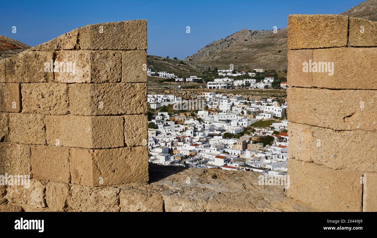 View through an old stone wall to a settlement with white houses and ...