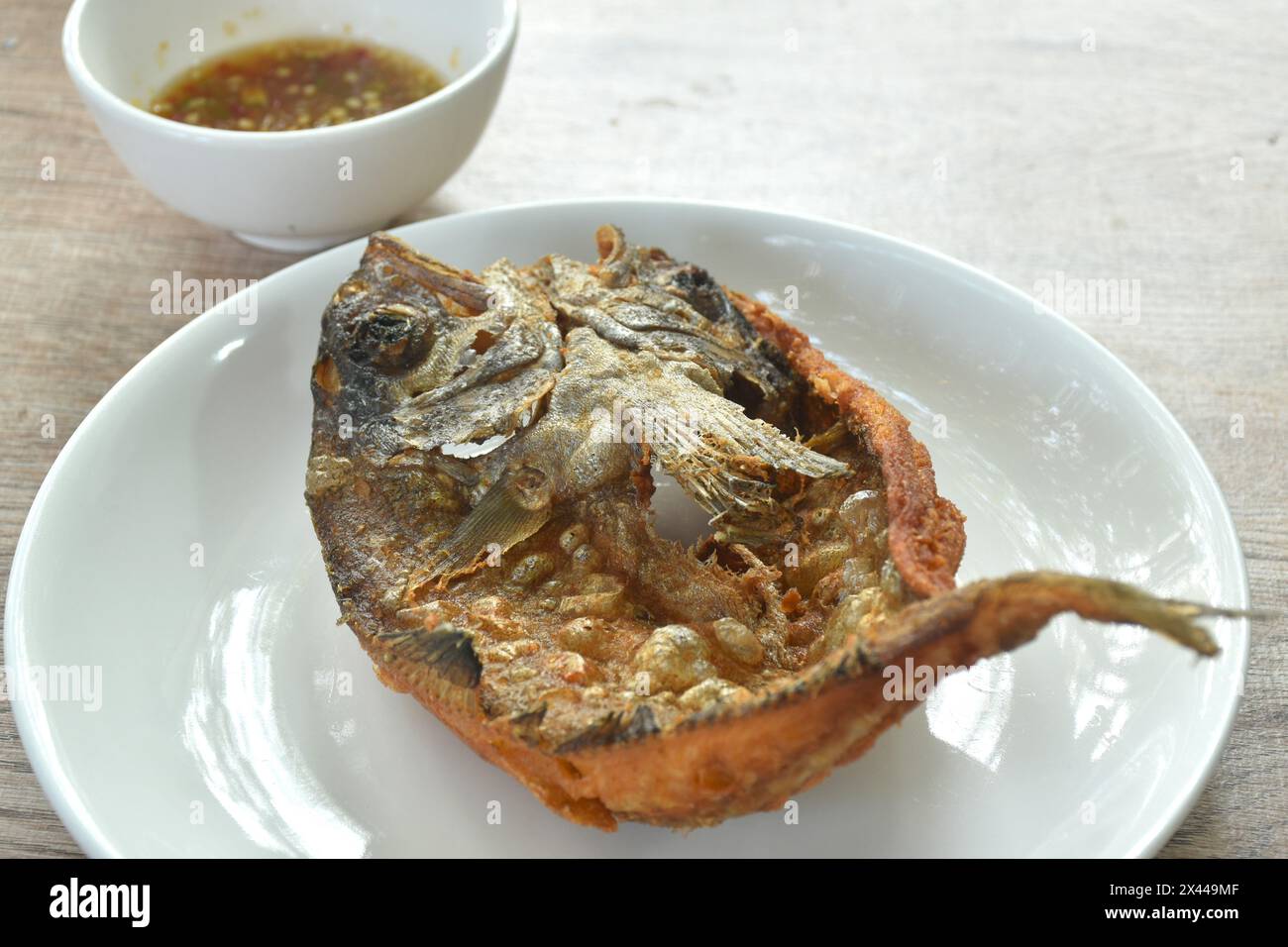 deep fried black-banded trevally fish on plate dipping spicy chili ...