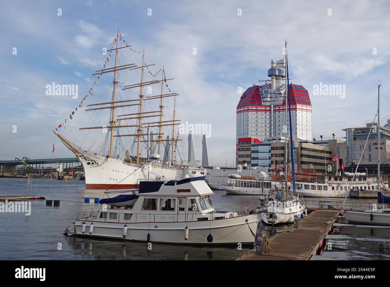 Sailing ship, small boats and a high-rise building in a harbour in ...