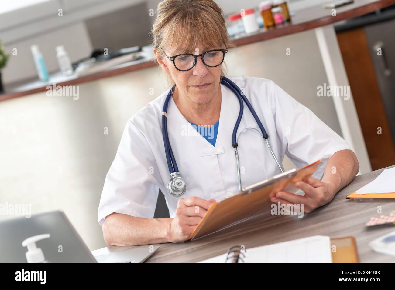 Female doctor reading a clinical record in medical office Stock Photo ...
