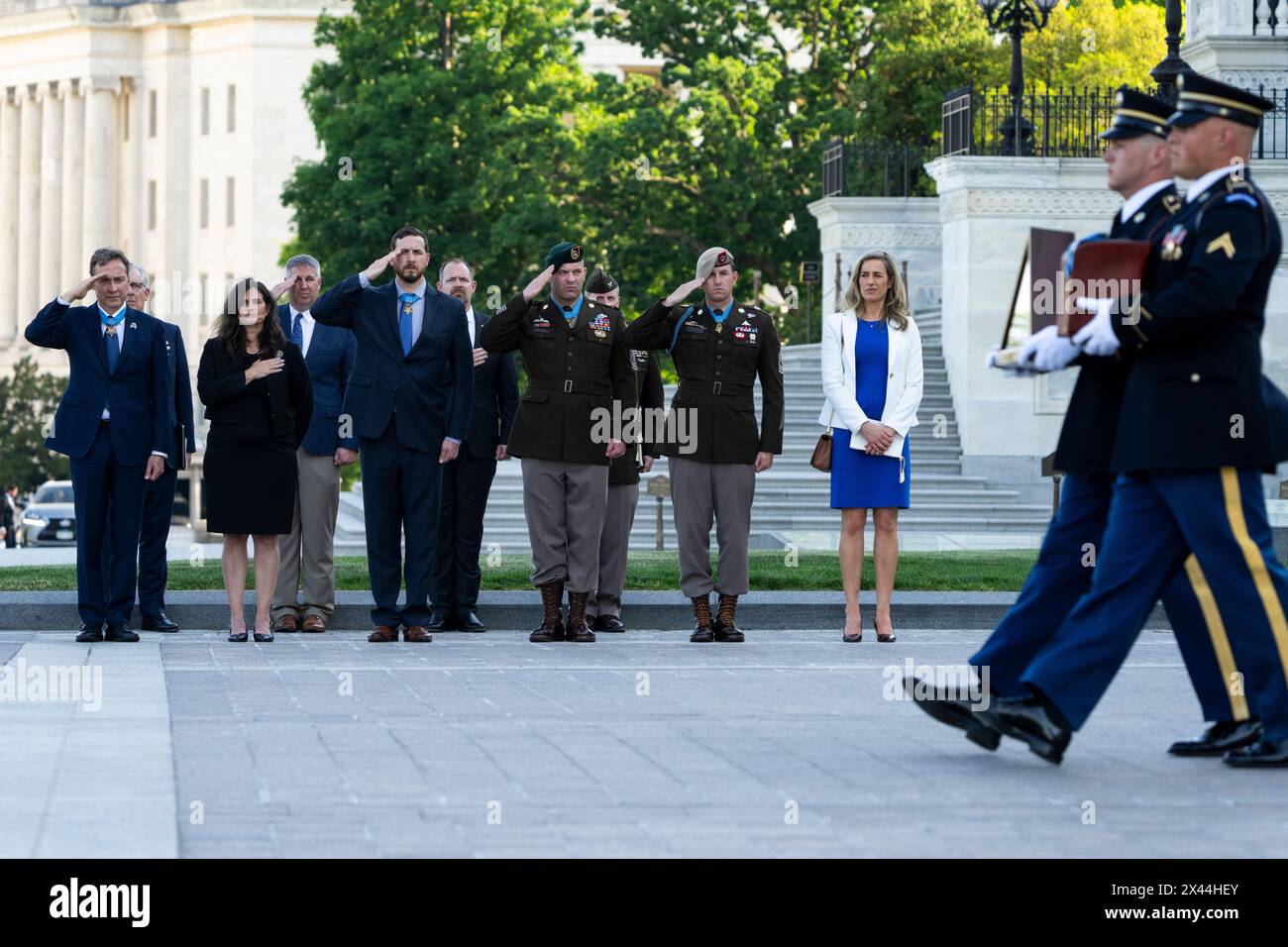 Medal of Honor recipients stand at attention as a military honor guard carries the urn of ...