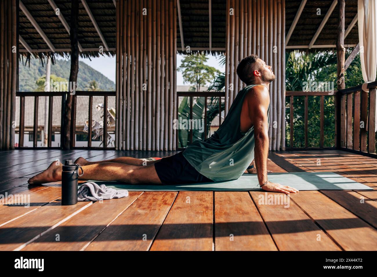 Side view of man practicing Cobra pose on exercise mat at wellness ...