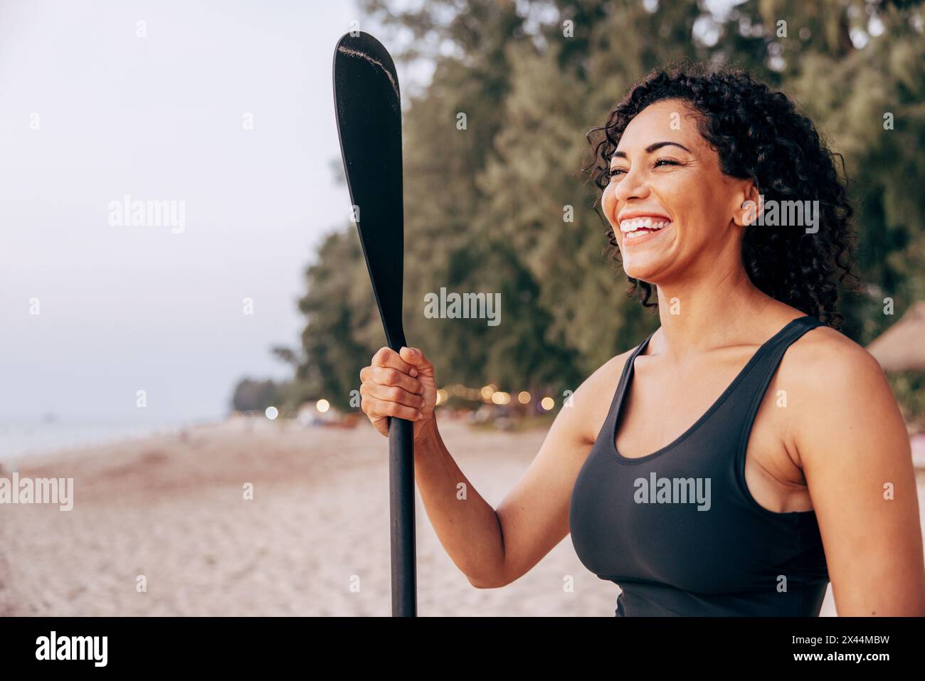 Happy mature woman holding oar at beach Stock Photo - Alamy