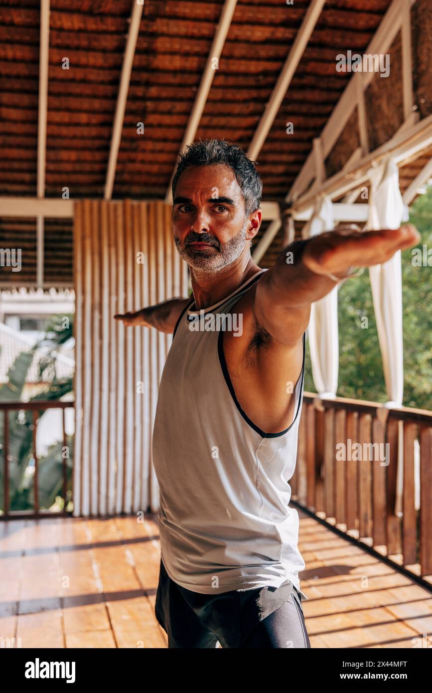 Determined man doing Warrior 2 pose at wellness resort Stock Photo - Alamy