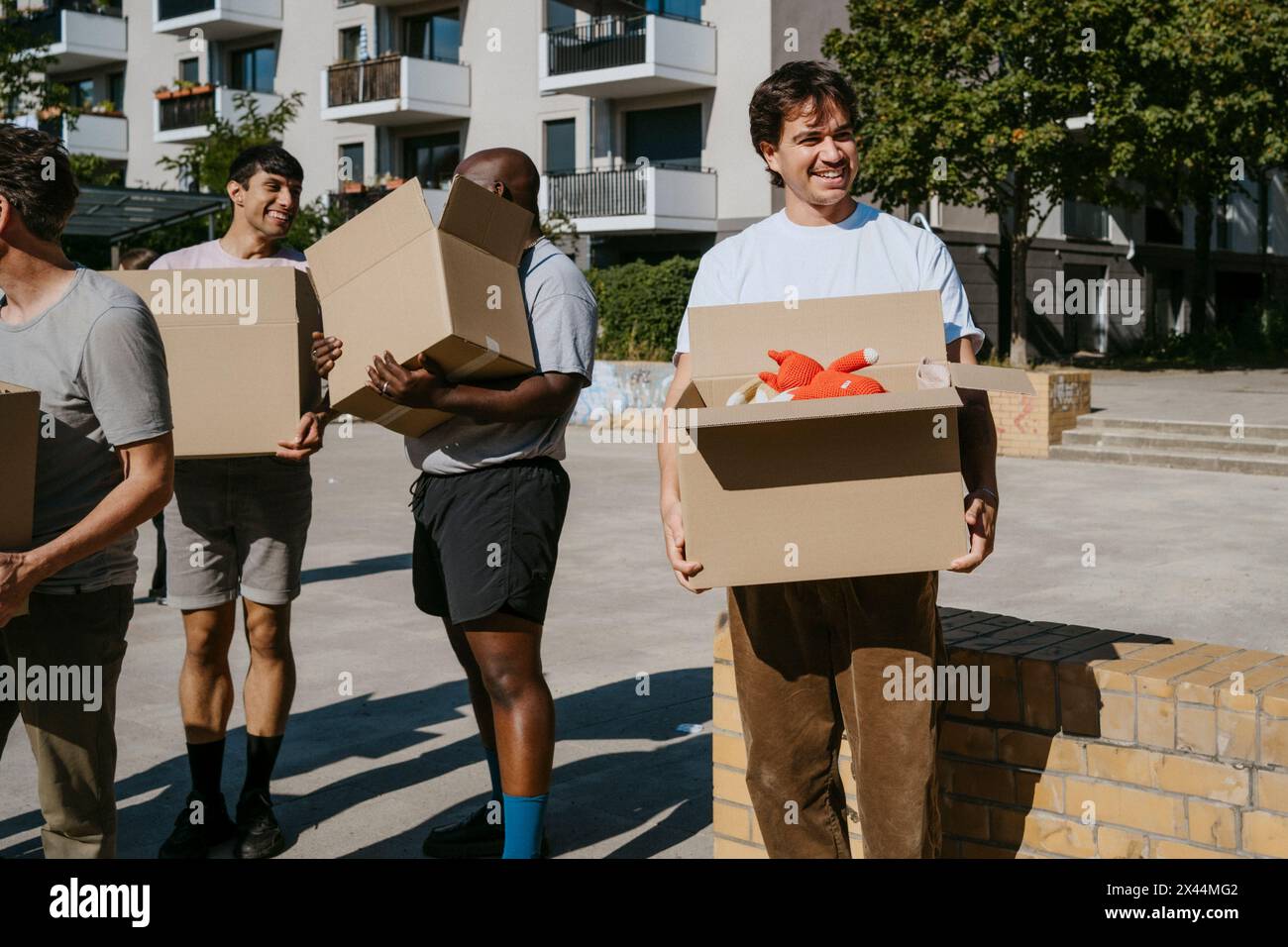 Multiracial group of volunteers holding cardboard boxes while working ...