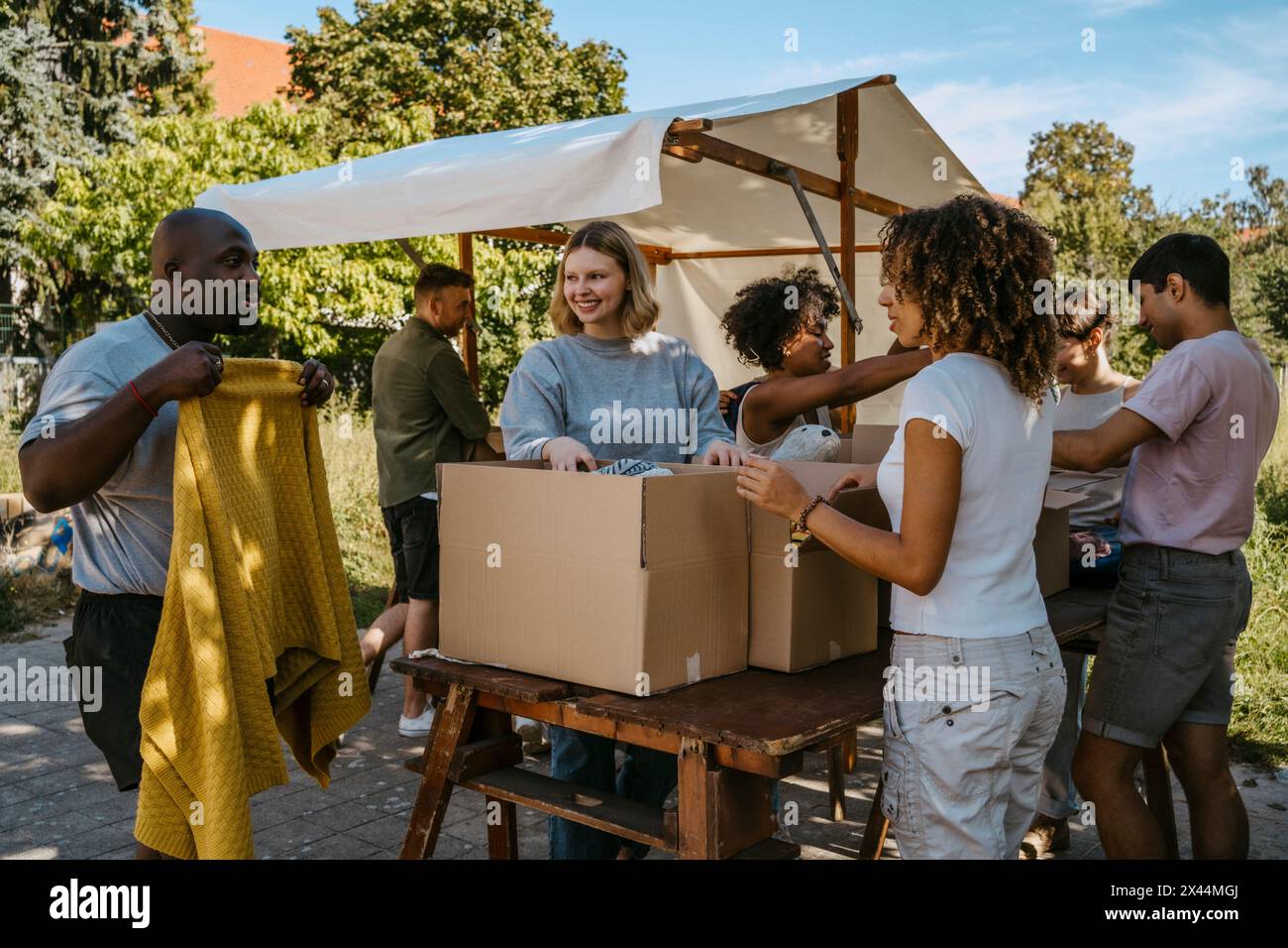 Smiling group of multiracial volunteers helping each other while ...