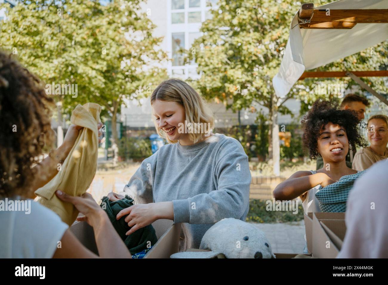 Happy volunteer helping team while sorting out clothes during charity ...