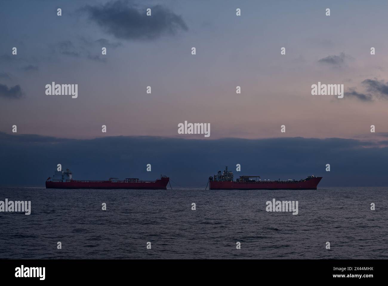 Silhouette of two oil tankers in the sea, early in the morning, with ...