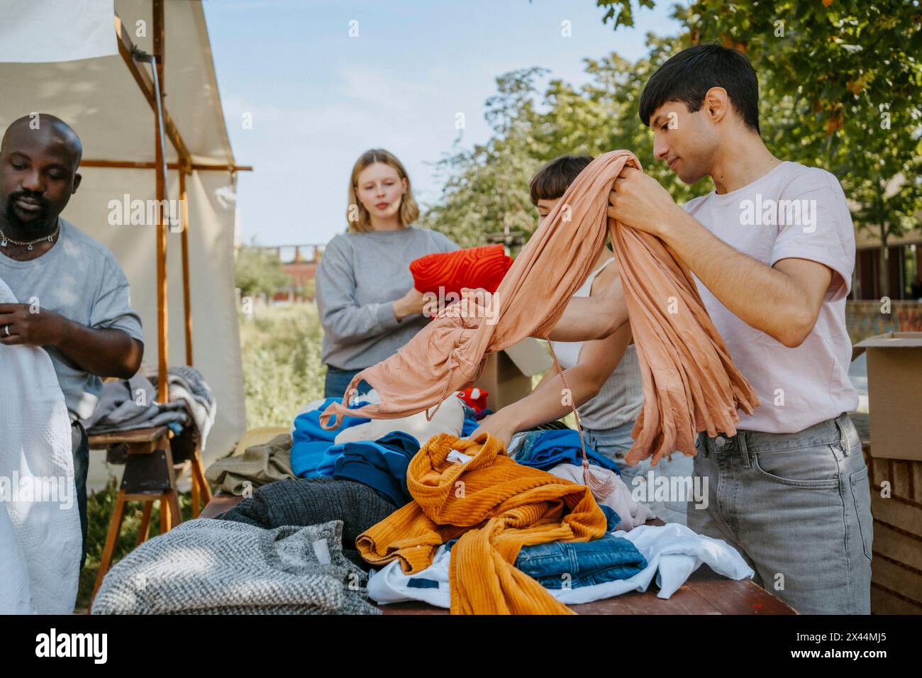 Group of multiracial volunteers sorting clothes on table during charity ...