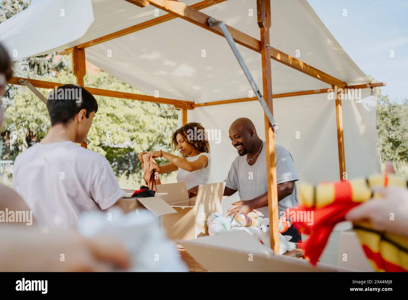 Smiling male volunteer helping female colleague while sorting out ...