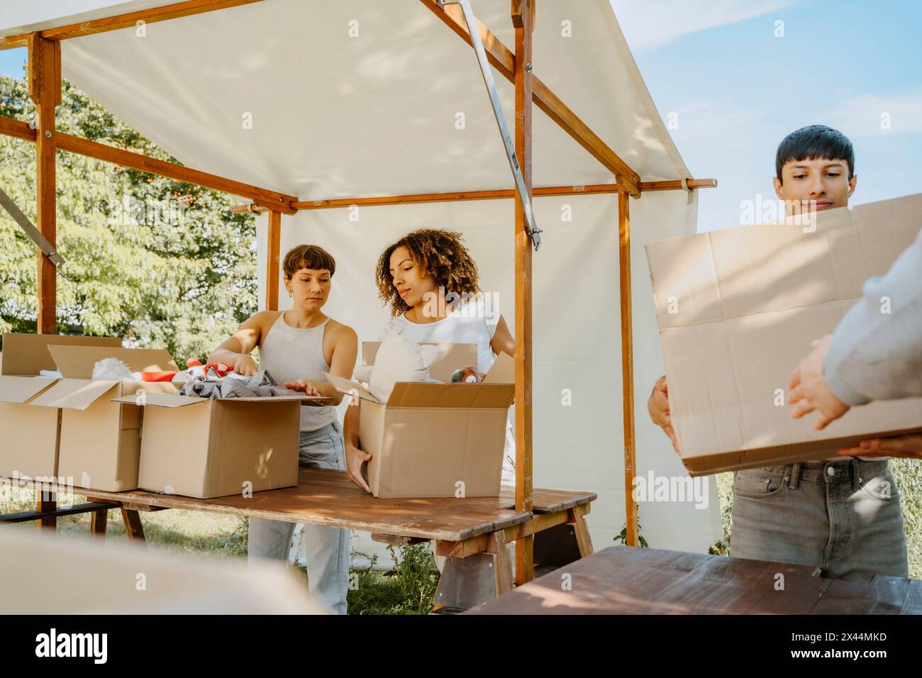 Female volunteers arranging boxes with donation goods on table during ...