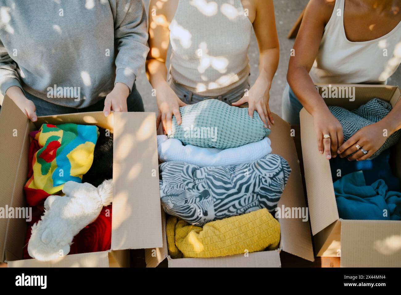 Midsection of multiracial volunteers with boxes of donation goods at ...