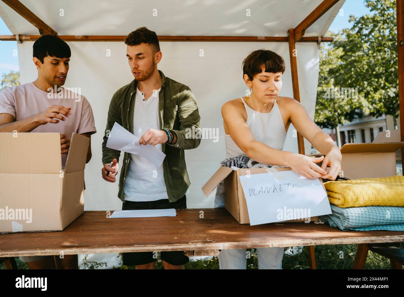 Group of male and female volunteers sticking name tags on boxes during ...