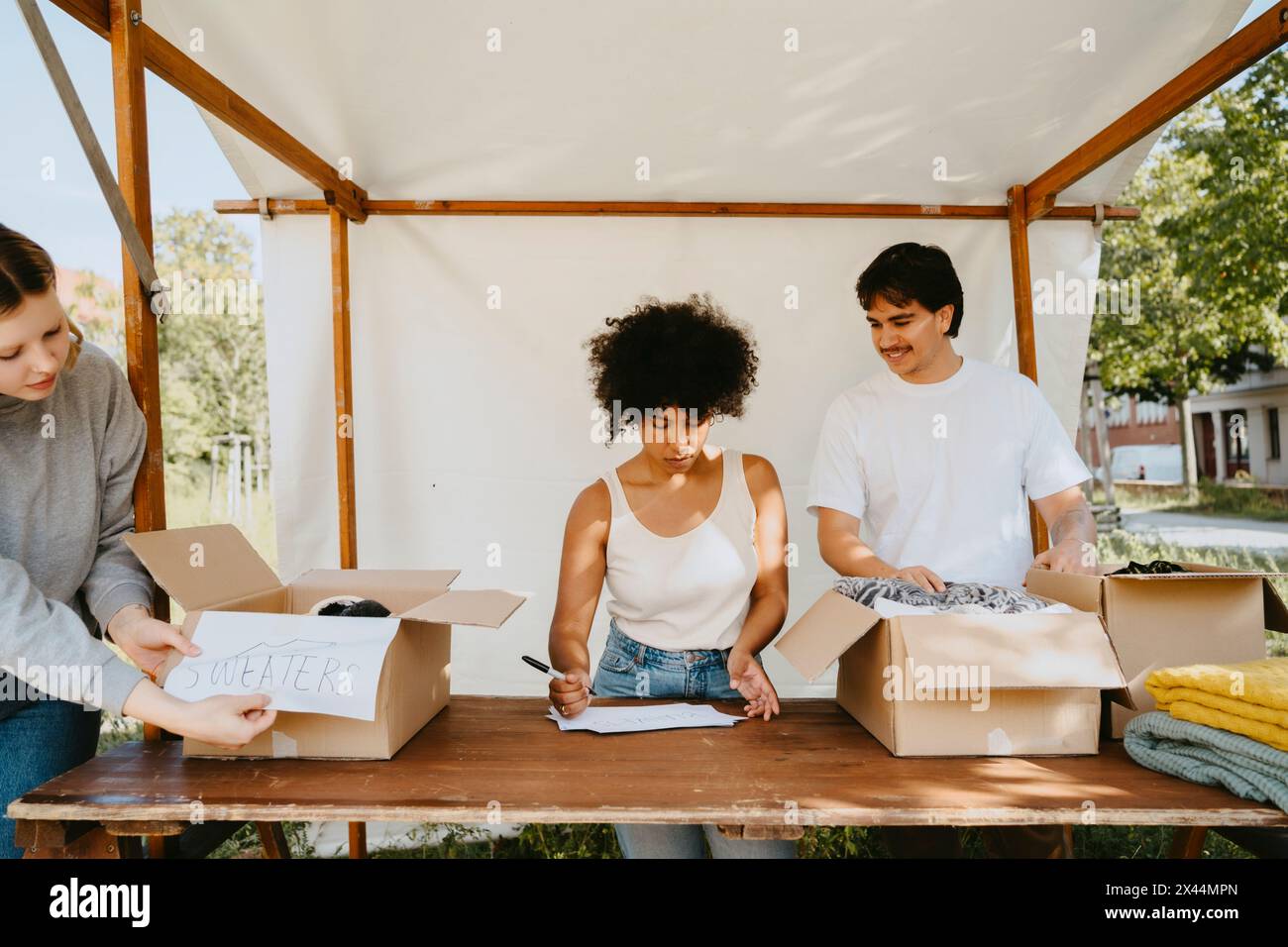 Group of multiracial volunteers labeling donation boxes during charity ...