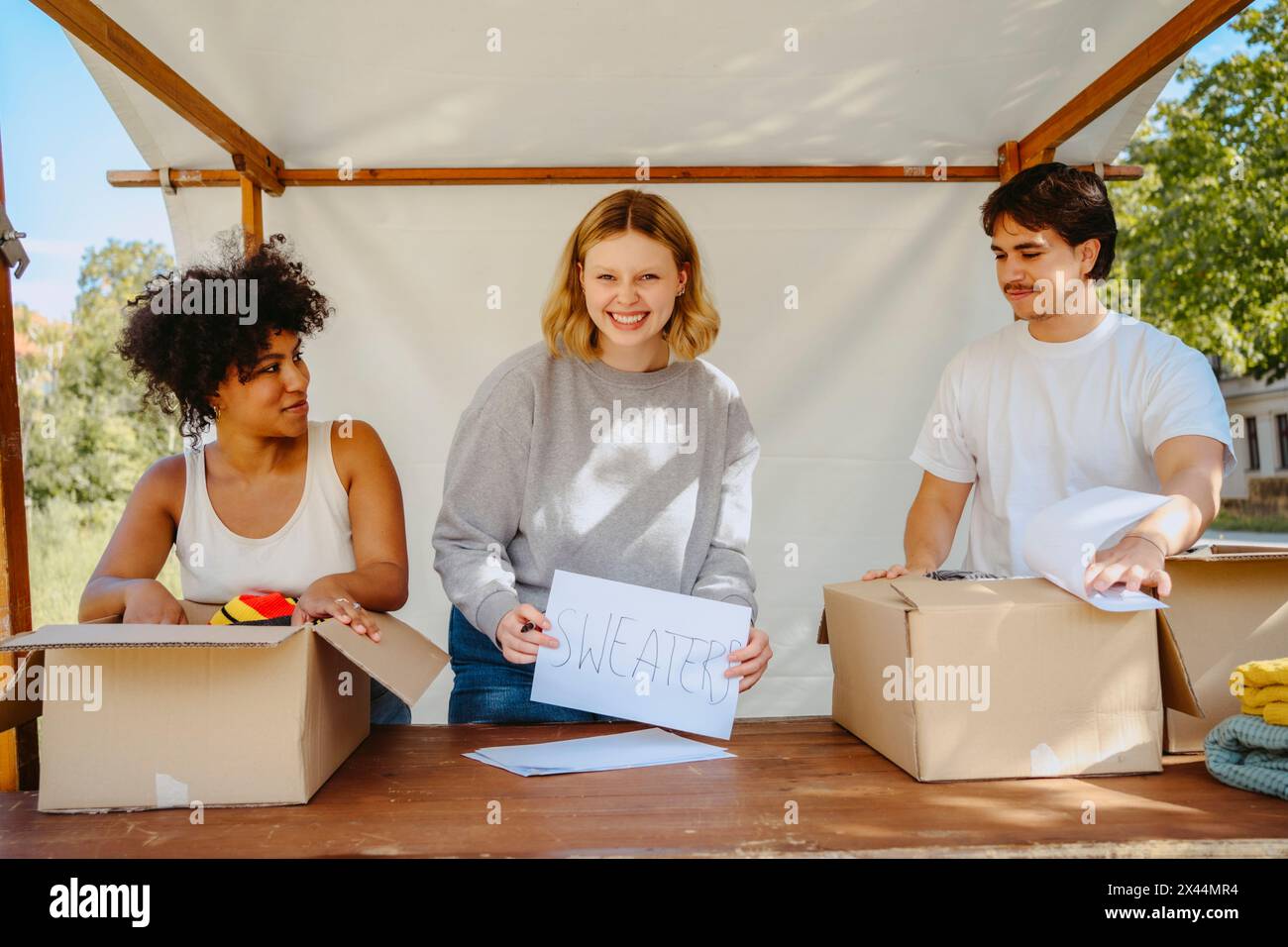 Portrait of happy volunteer holding name tag with male and female ...